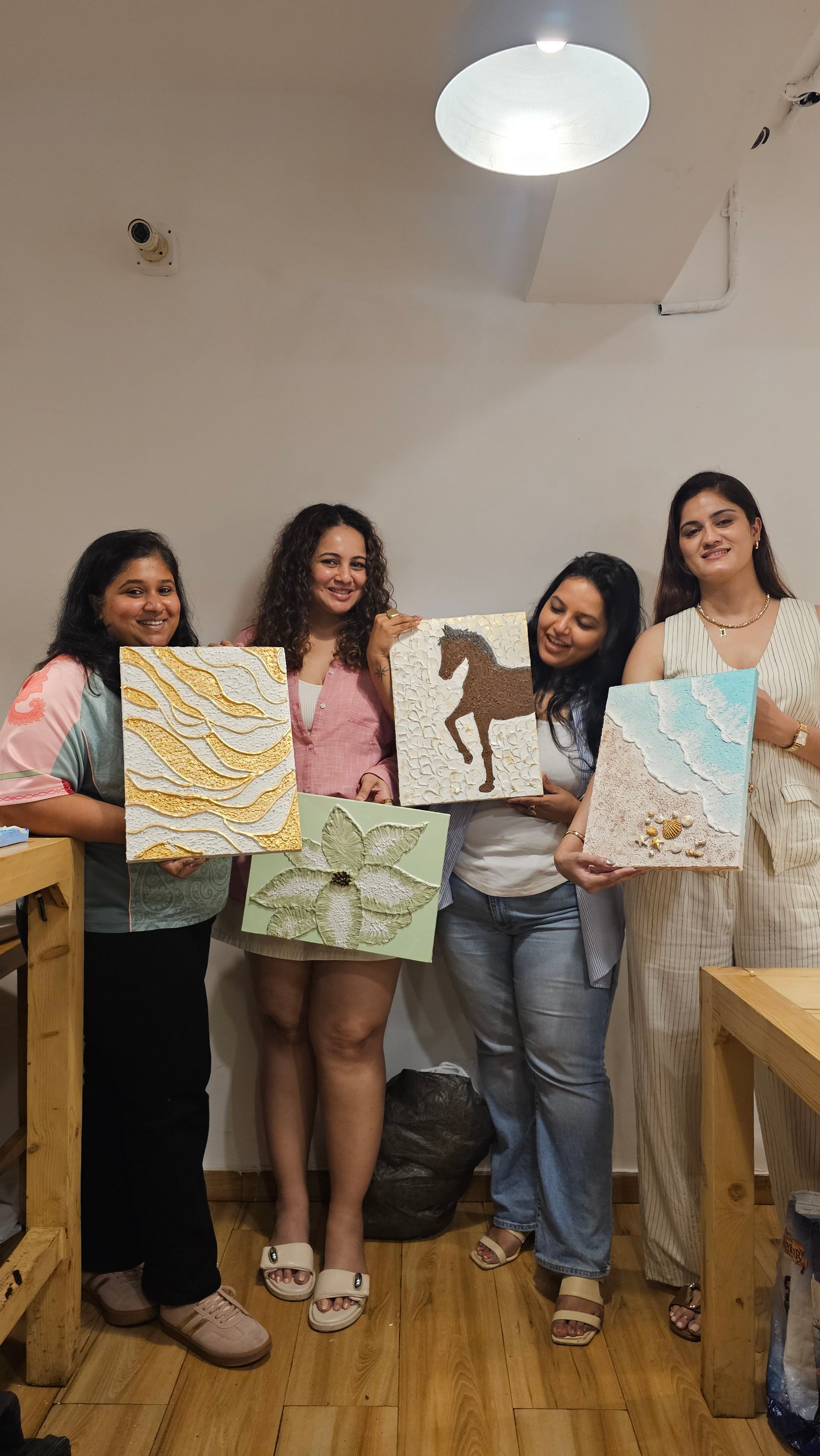 Four women standing together with textured artworks